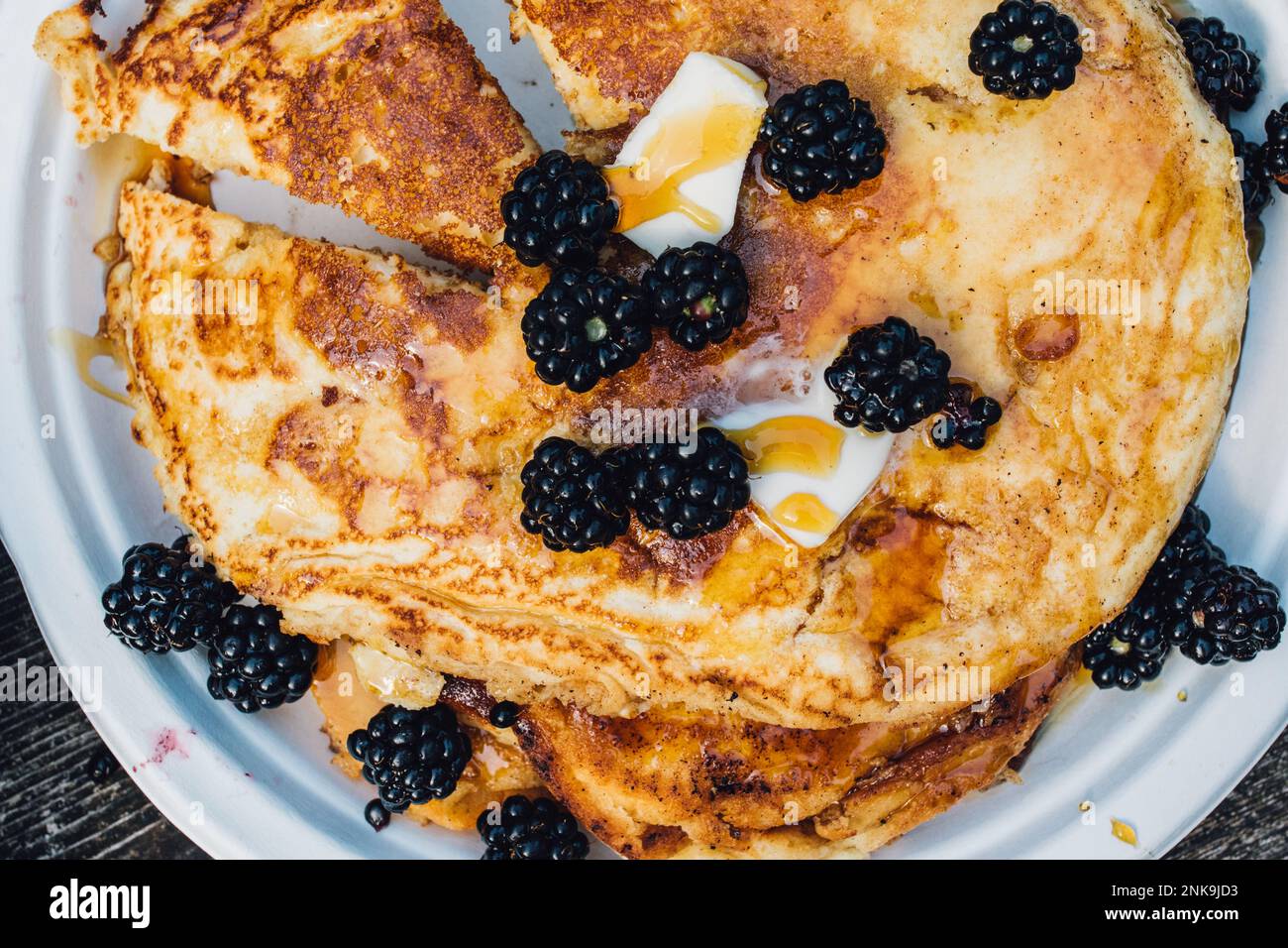 top down view of stack of pancakes with blackberries, maple syrup ...