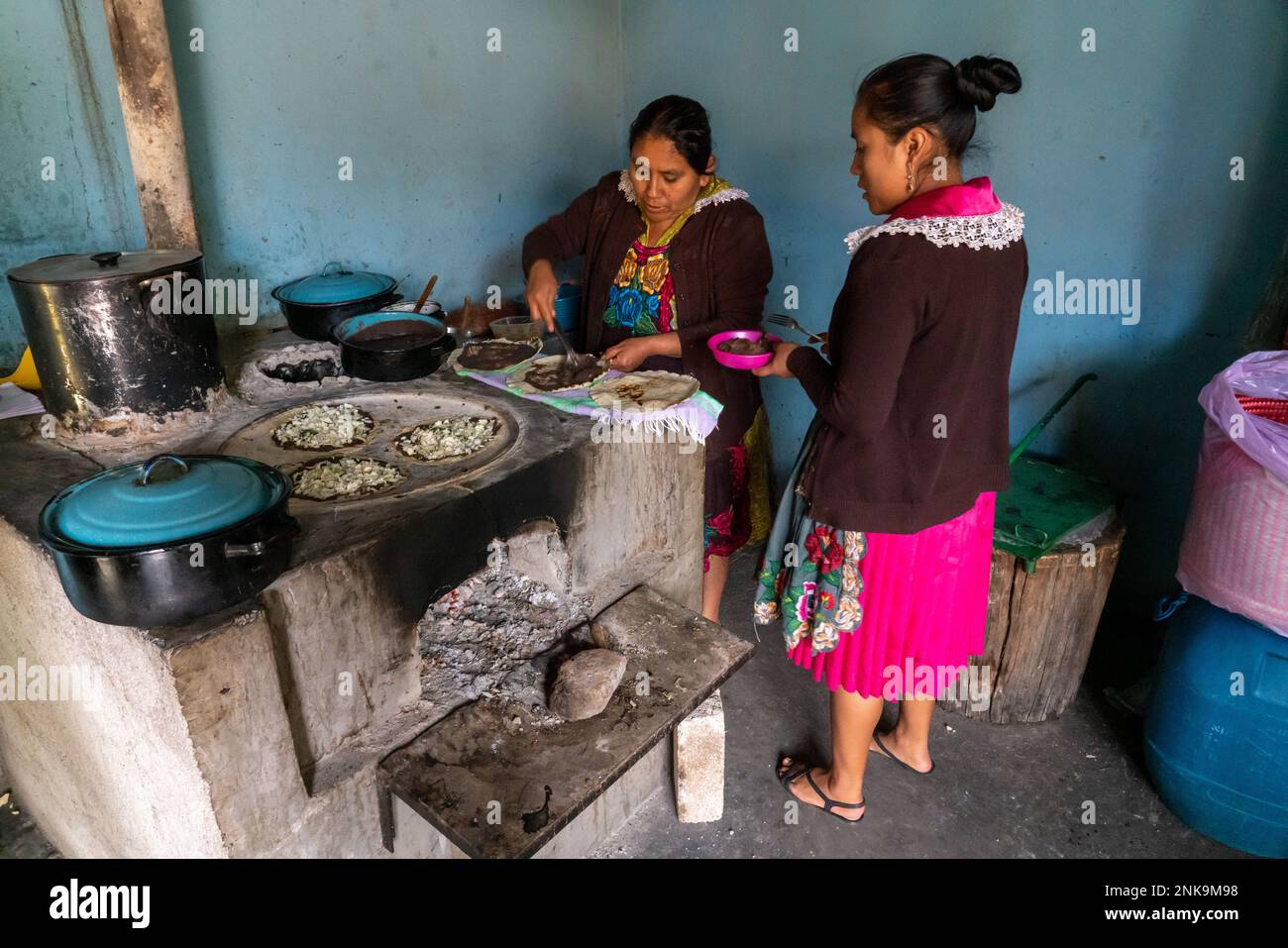 Indigenous Zapotec women in traditional dress cook memelas on a comal ...