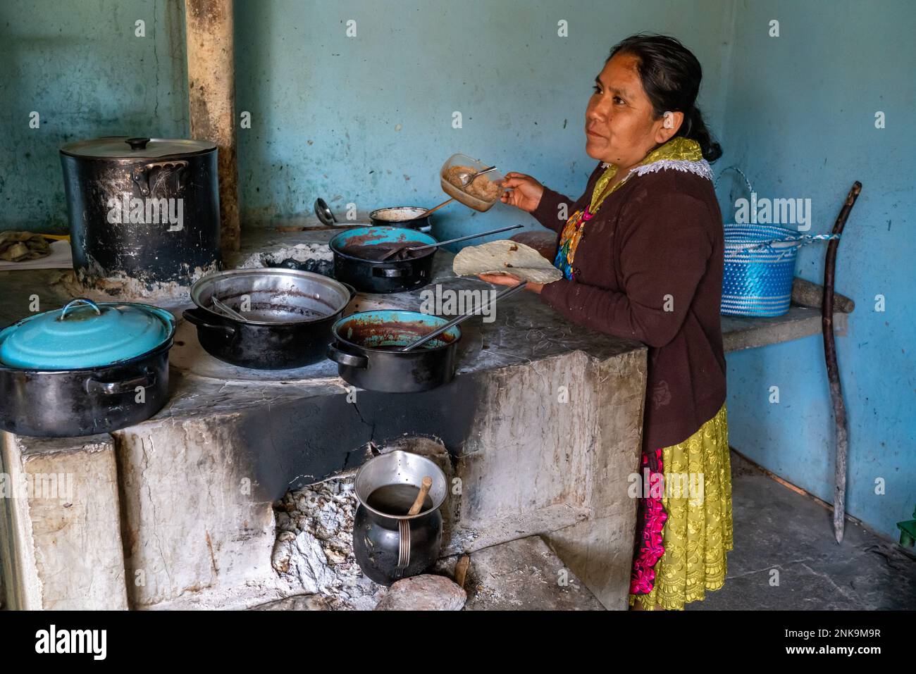 An indigenous Zapotec woman in traditional dress cooks a meal on a ...