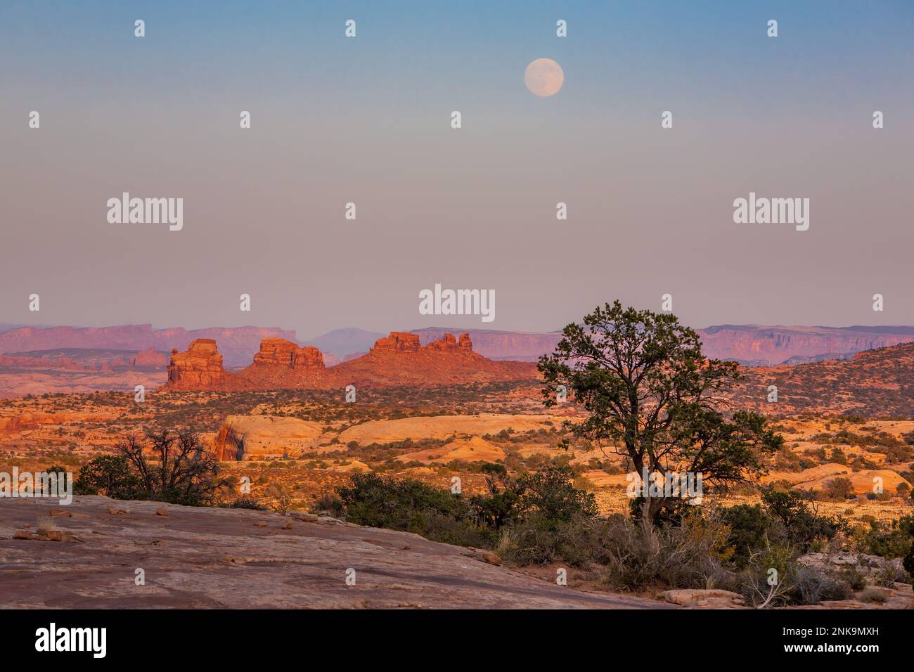 Moon rising over Arth's Rim at sunset near Moab, Utah. While the moon ...