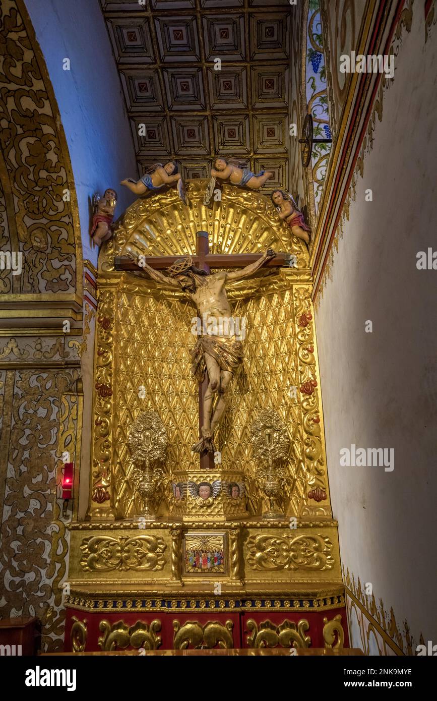 A statue of the crucified Christ in a side chapel in the ornate Baroque ...