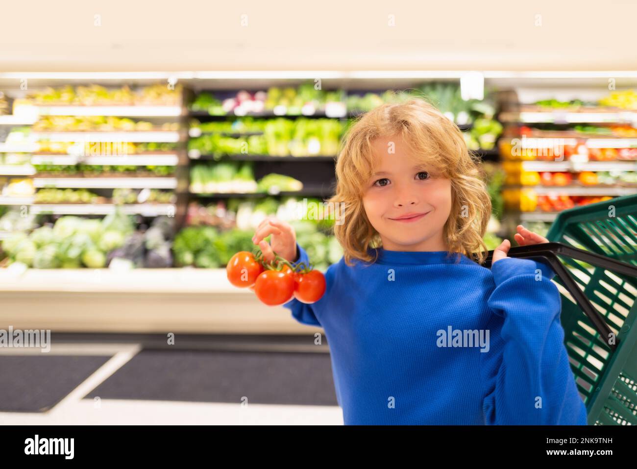Child with fresh tomato vegetables. Portrait of child in a food store ...