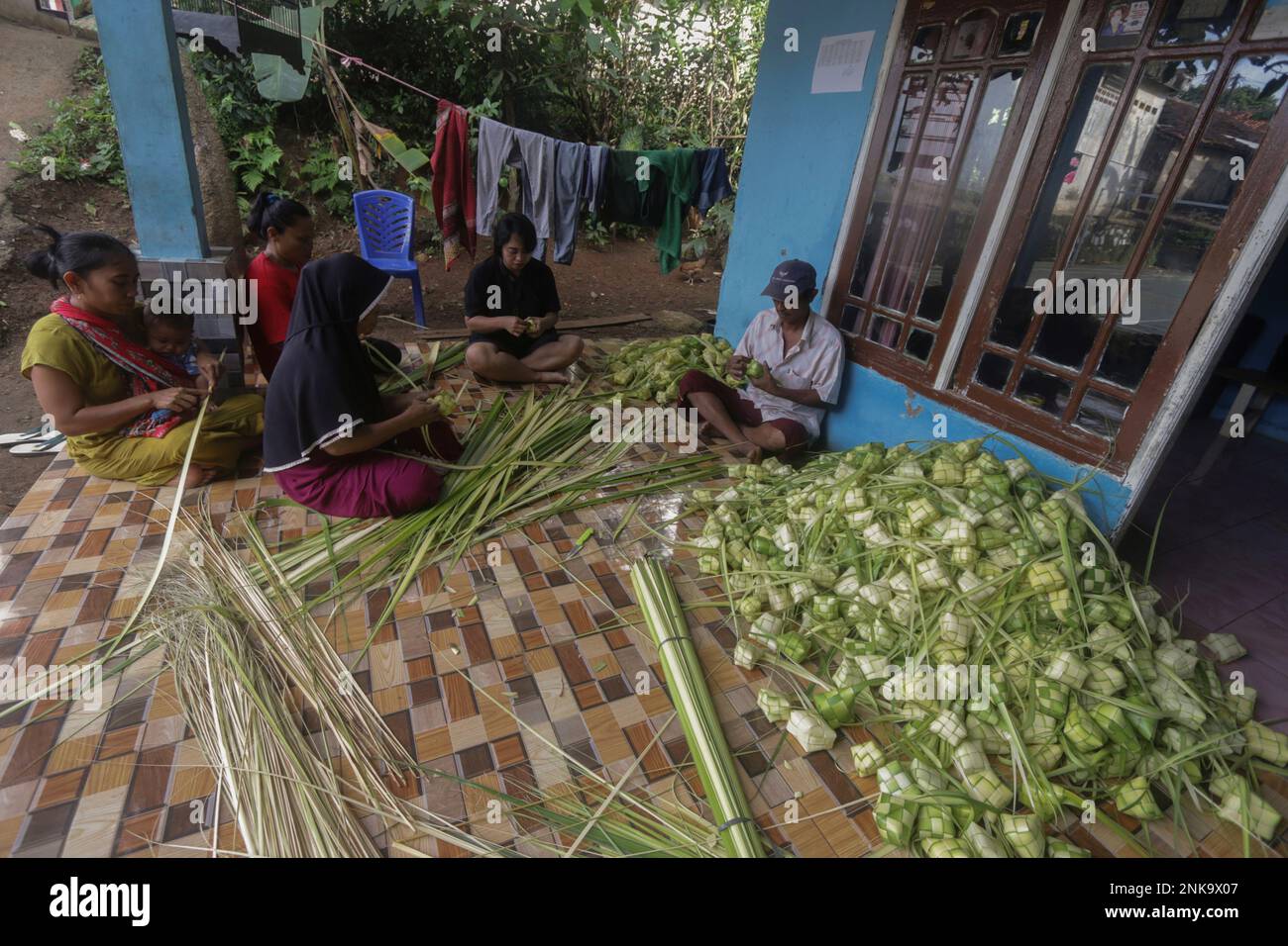 Indonesian vendors weave palm leaves used to make traditional rice ...