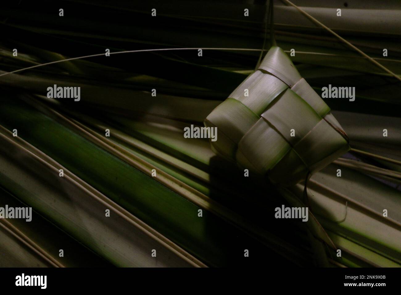 Indonesian vendors weave palm leaves used to make traditional rice ...