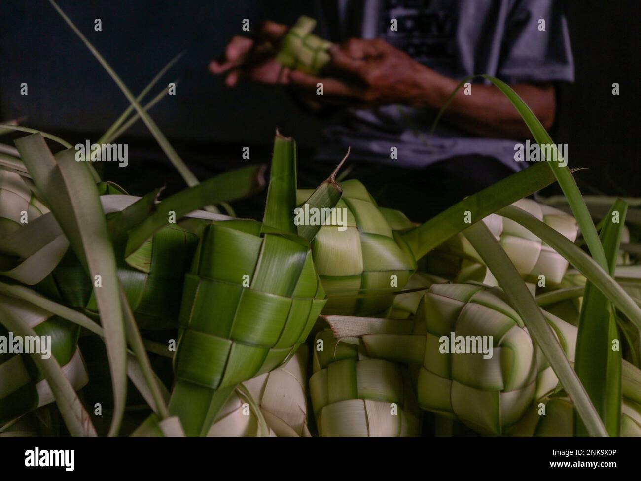 Indonesian vendors weave palm leaves used to make traditional rice ...
