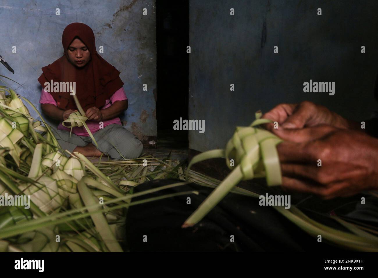 Indonesian vendors weave palm leaves used to make traditional rice ...