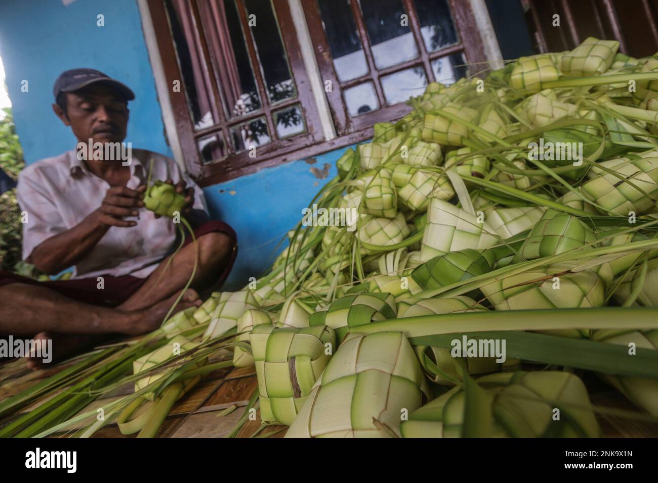 Indonesian vendors weave palm leaves used to make traditional rice ...