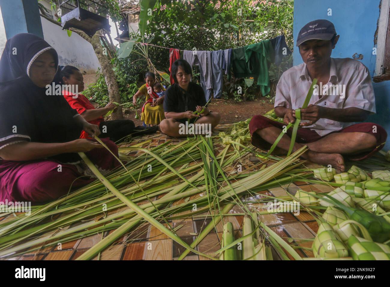 Indonesian vendors weave palm leaves used to make traditional rice ...