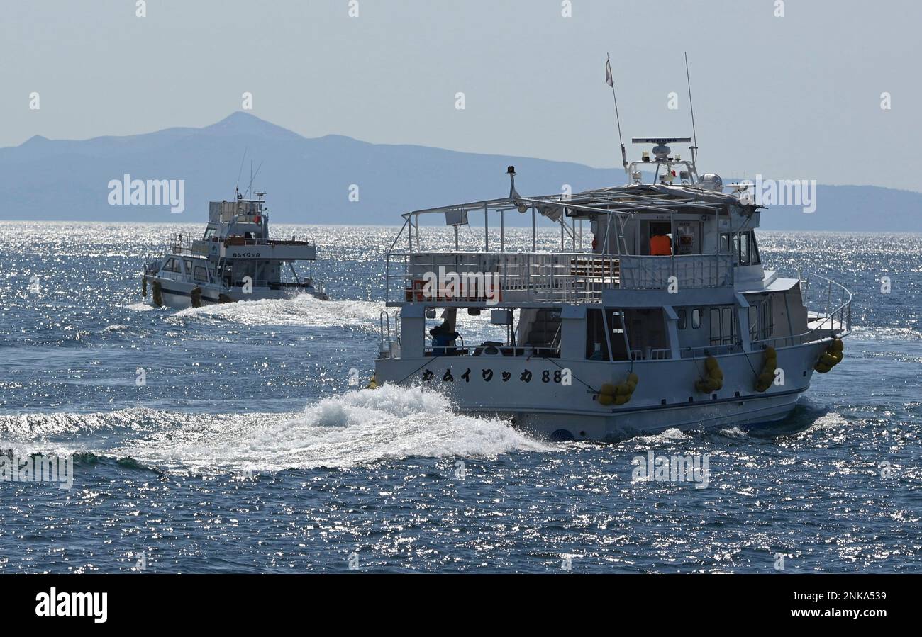 Sightseeing vessels leave a port for a searching in Rausu Town ...