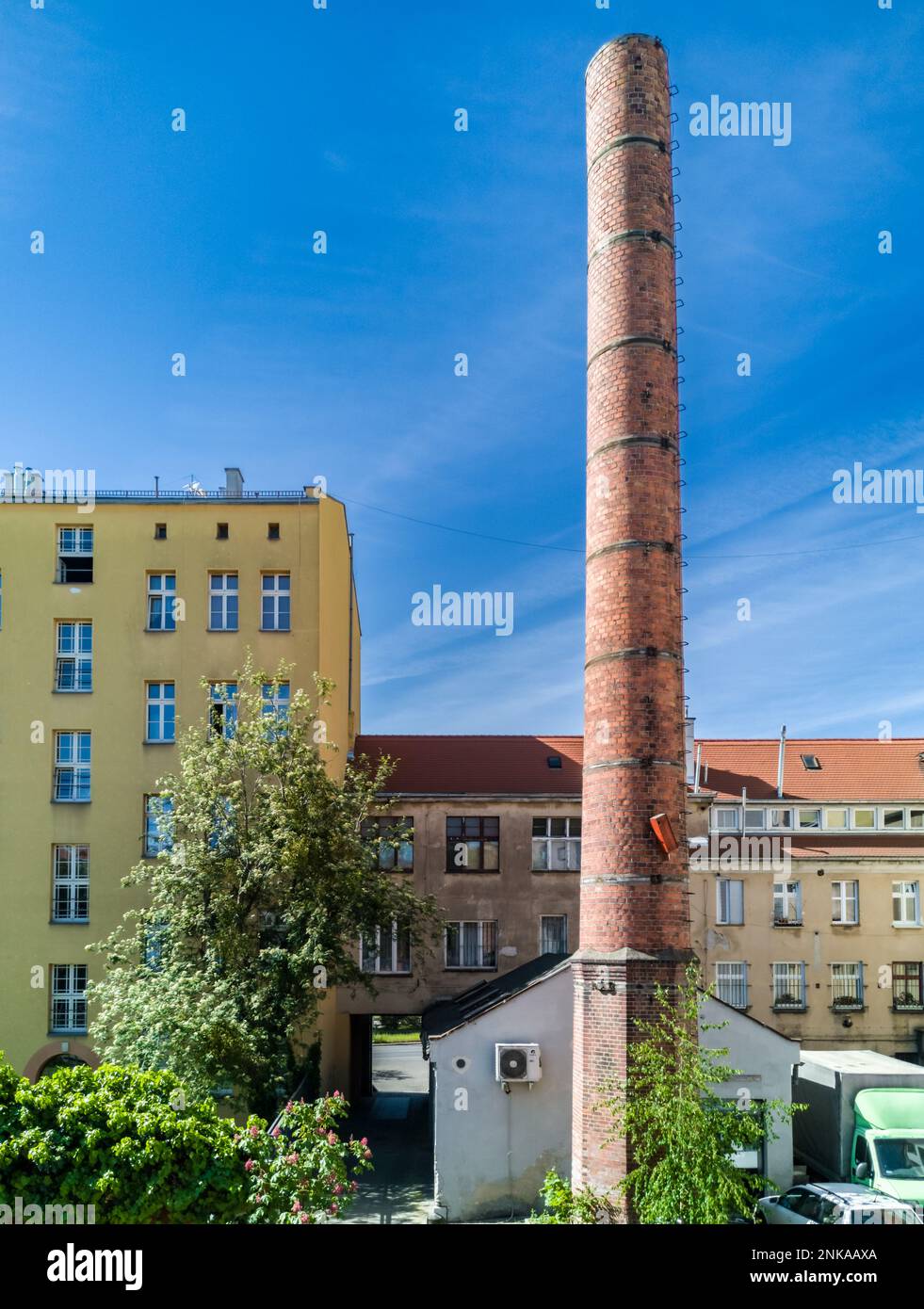 Window view to old tenement houses and high red brick chimney at sunny ...