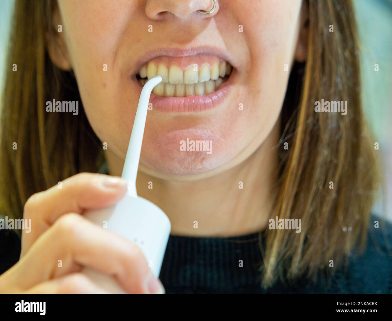 Healthy Oral Hygiene: Young woman Using domestic dental water flosser ...