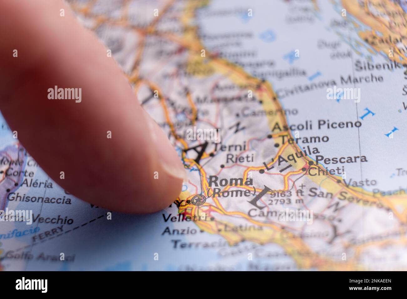 Finger pointing to Rome, Italy on detailed map with selective focus ...
