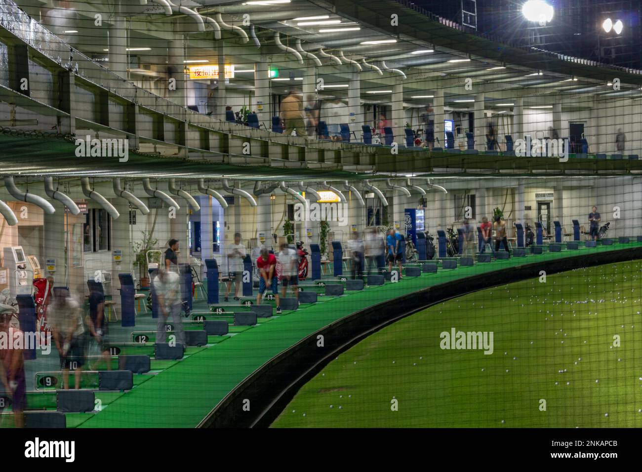 Night view of outdoor golf driving practice range with netting ...
