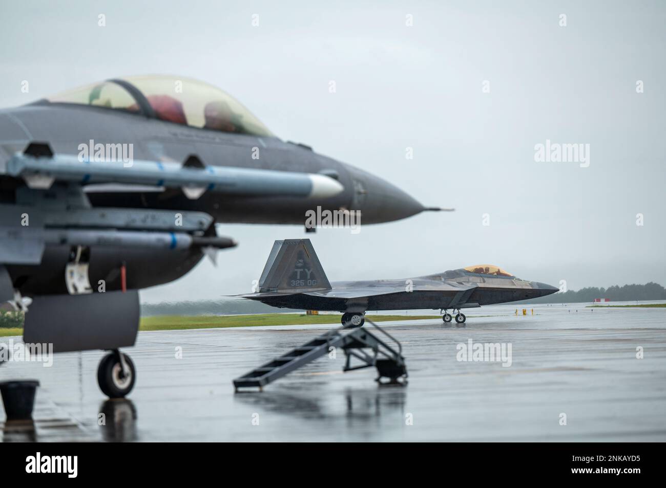 A U.S. Air Force F-16 Fighting Falcon and F-22 Raptor sit on the ...