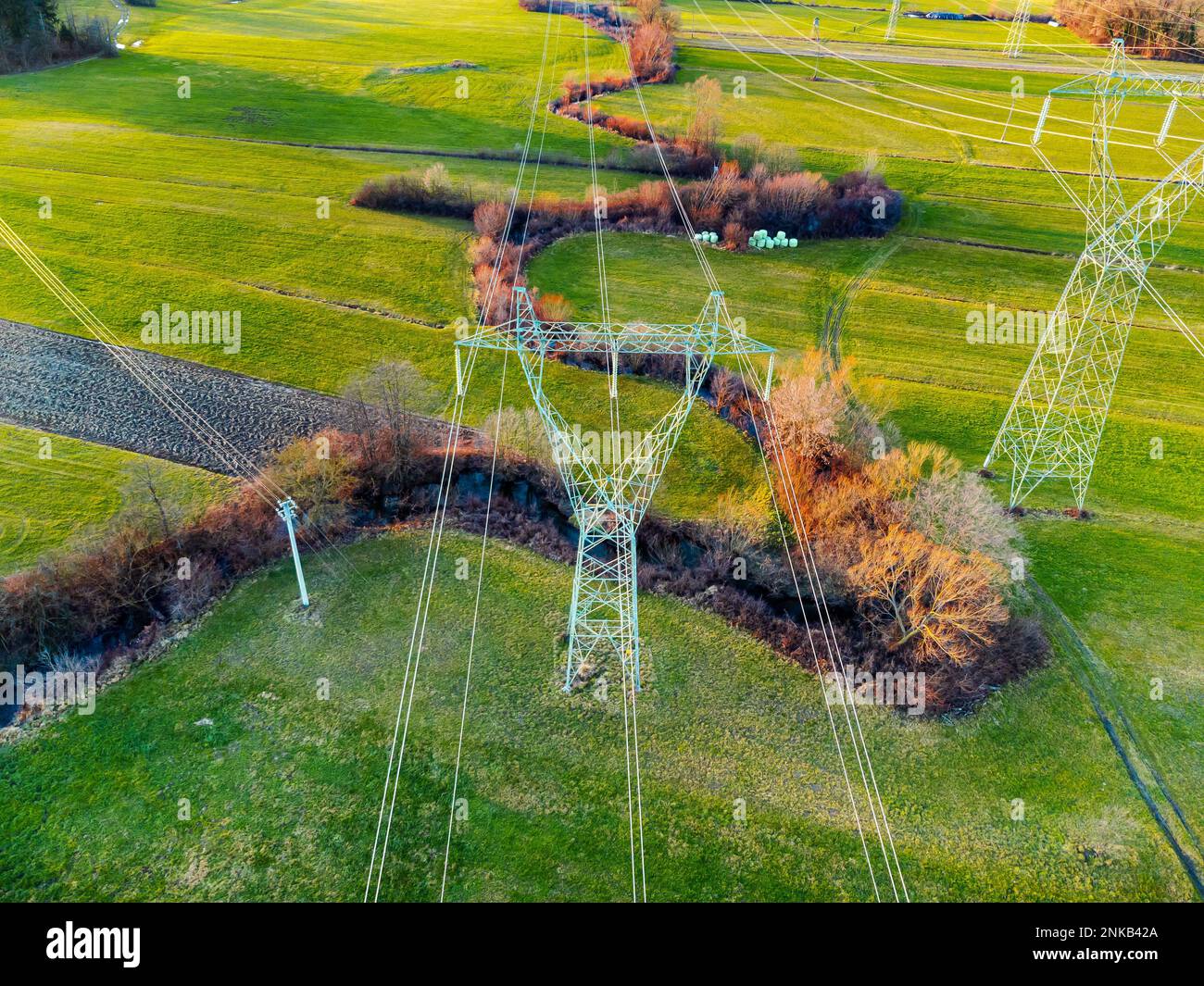 High voltage power transmission towers near a winding creek. Drone ...