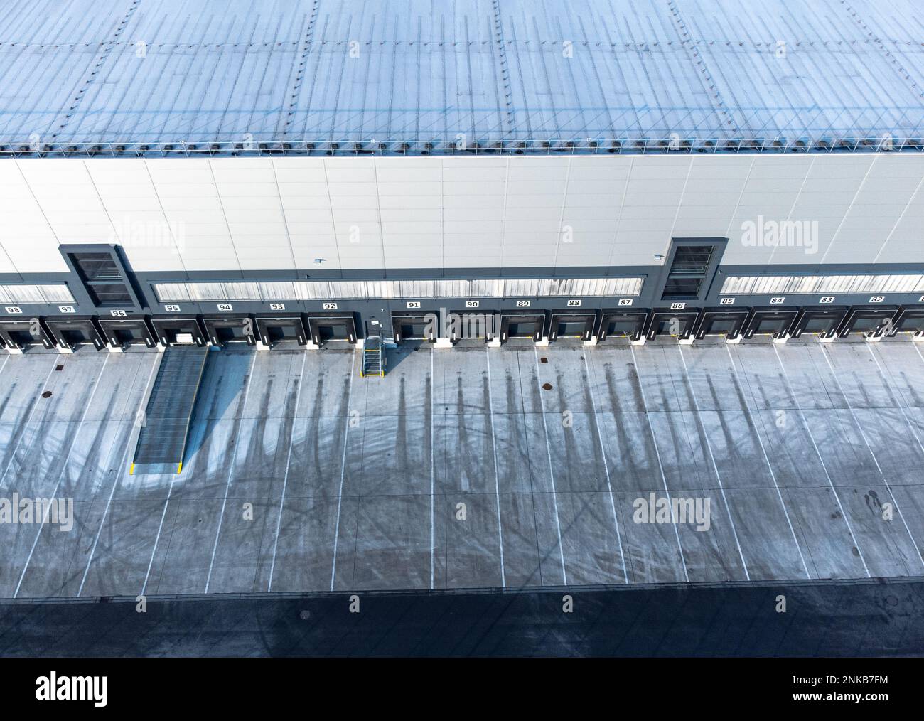 Large distribution warehouse exterior with loading ramp aerial top down ...