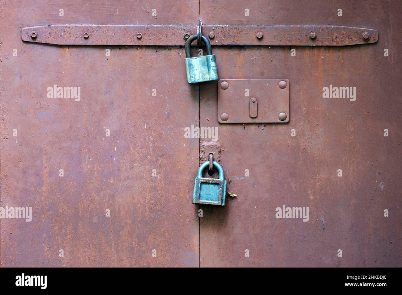 Old rusting metal gate with two padlocks. Space for lettering or design ...