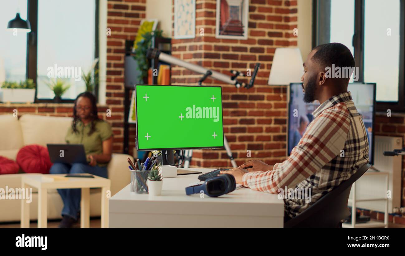 African american man analyzing greenscreen display on computer, looking ...