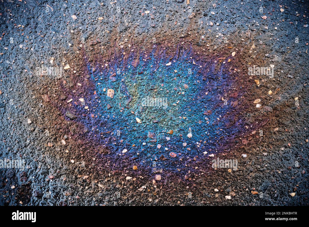 Colored oil stain on the asphalt. A rainbow slick of gasoline. Abstract ...