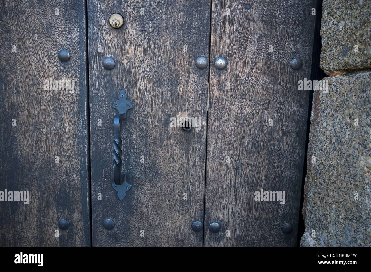 Old and modern lock on old dark door with iron handle in horizontal ...