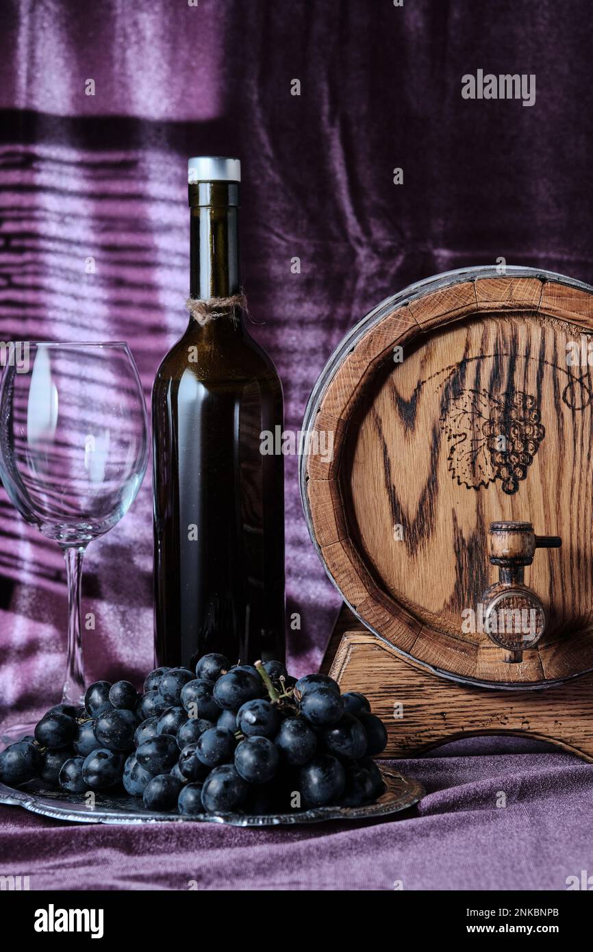 Still life of grapes and wine. Wooden barrel, berries and bottle on a ...