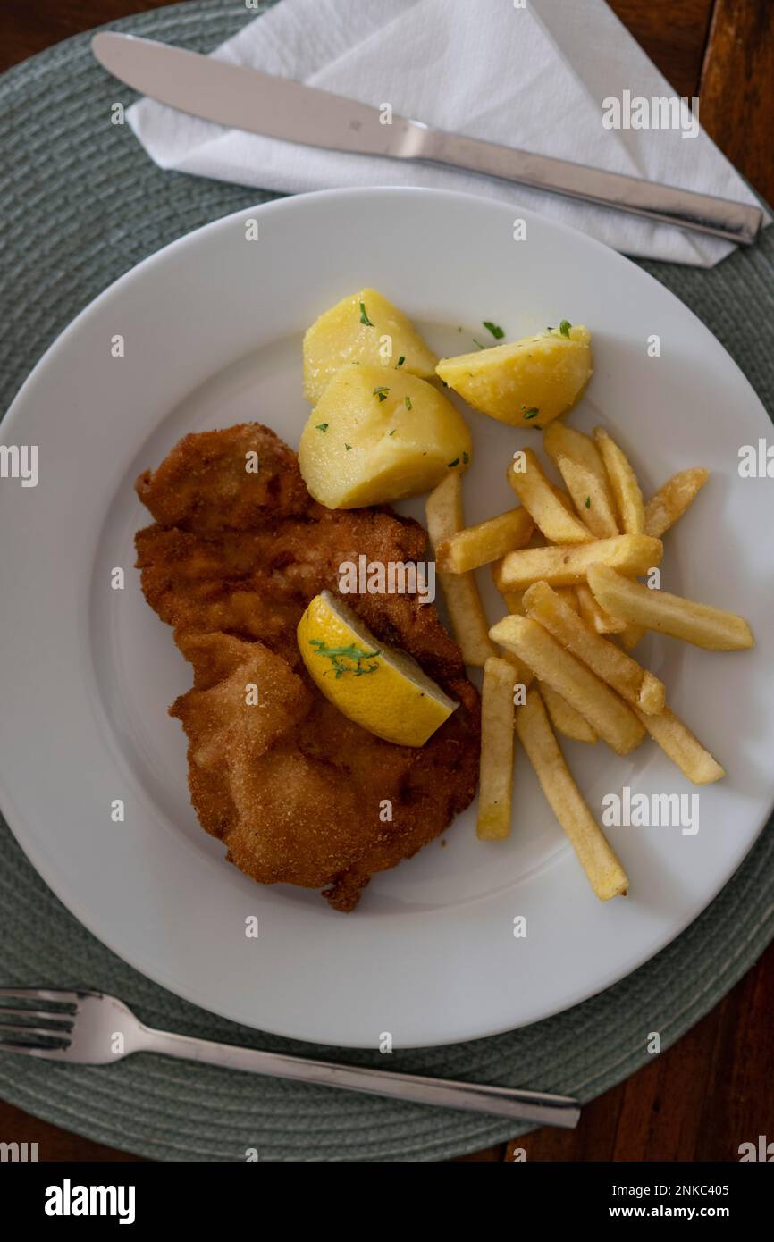 Wiener Schnitzel with parsley potatoes and french fries Stock Photo - Alamy