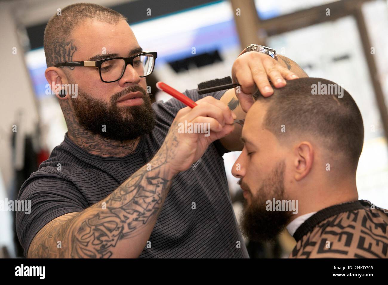 Barber Eddie Rivera uses a straight razor while giving a haircut to ...