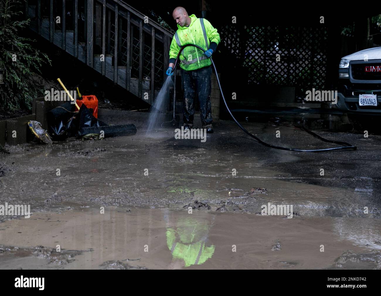 A man who did not give his name works to wash mud from a driveway along ...