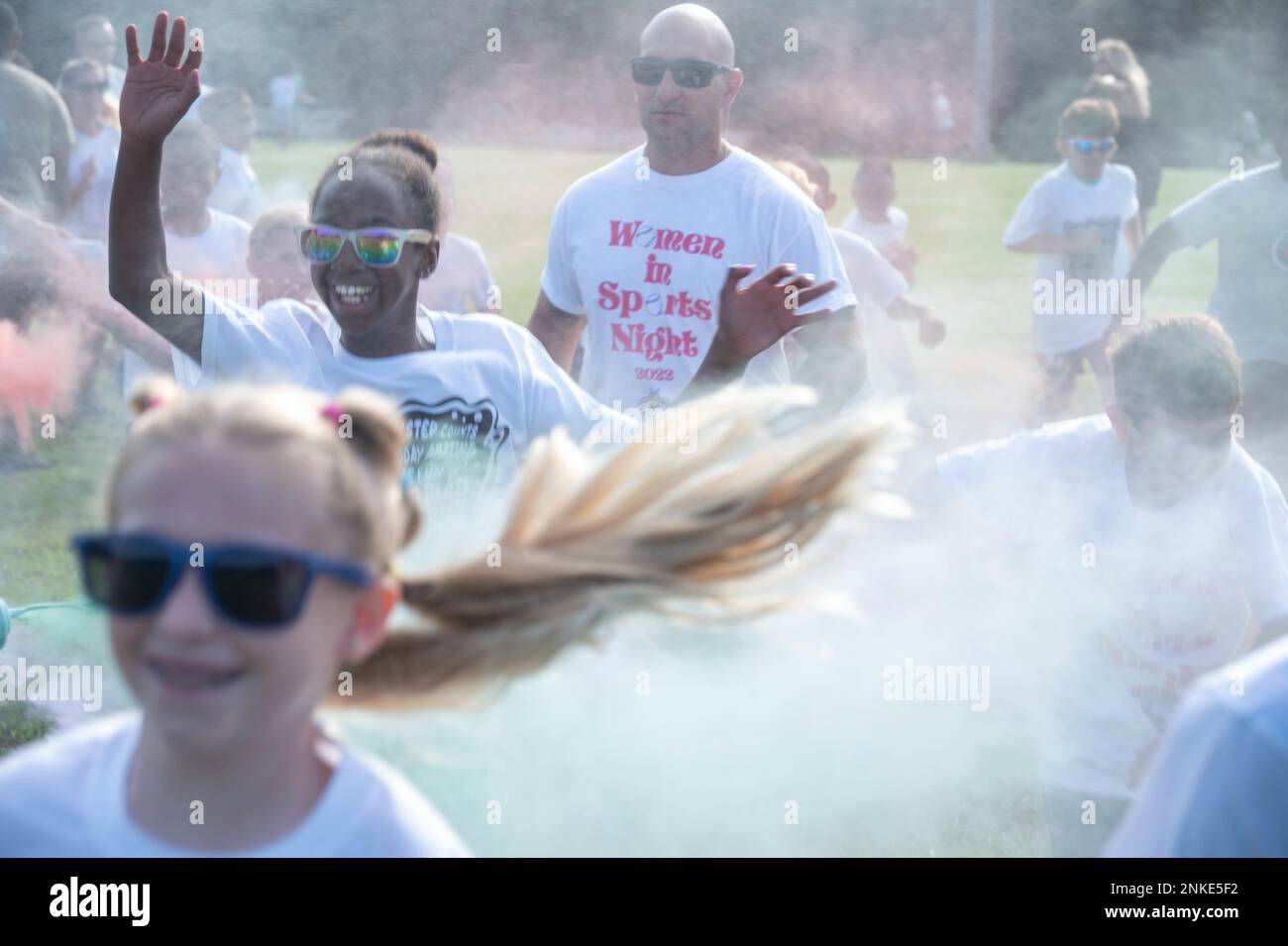 Children and their family members run through clouds of powdered color ...