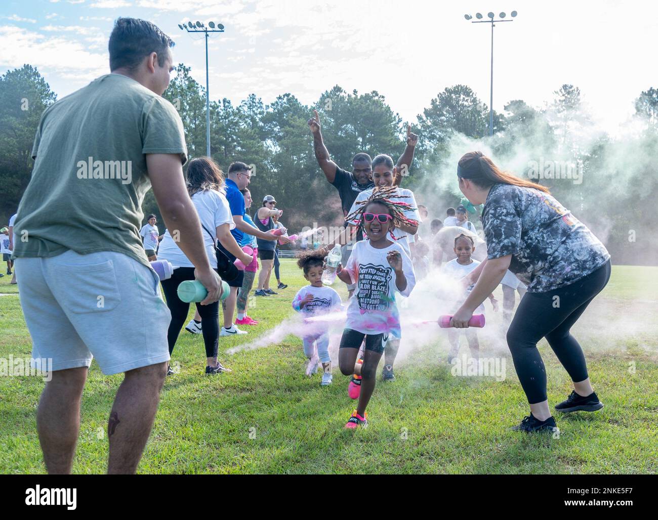 Children and their family members run through clouds of powdered color ...