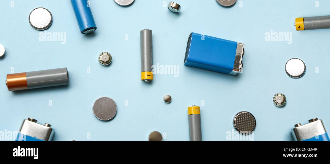 Different batteries on light blue background Stock Photo - Alamy