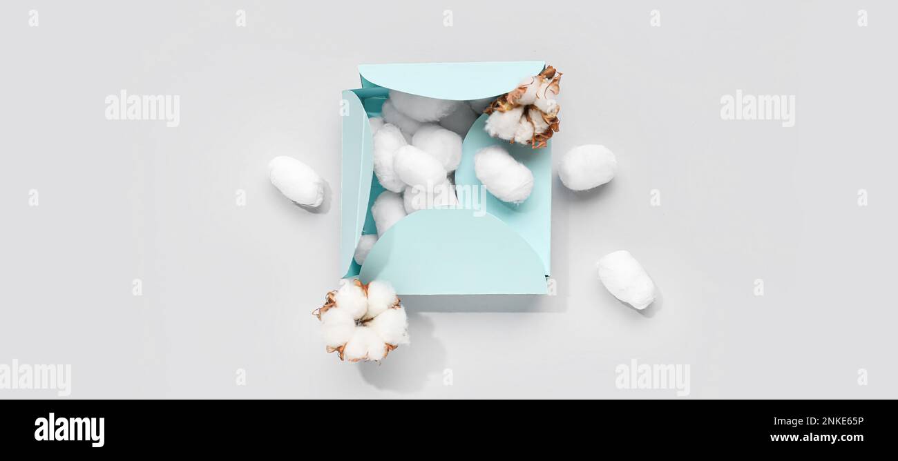 Box with soft cotton balls and flowers on light background Stock Photo ...