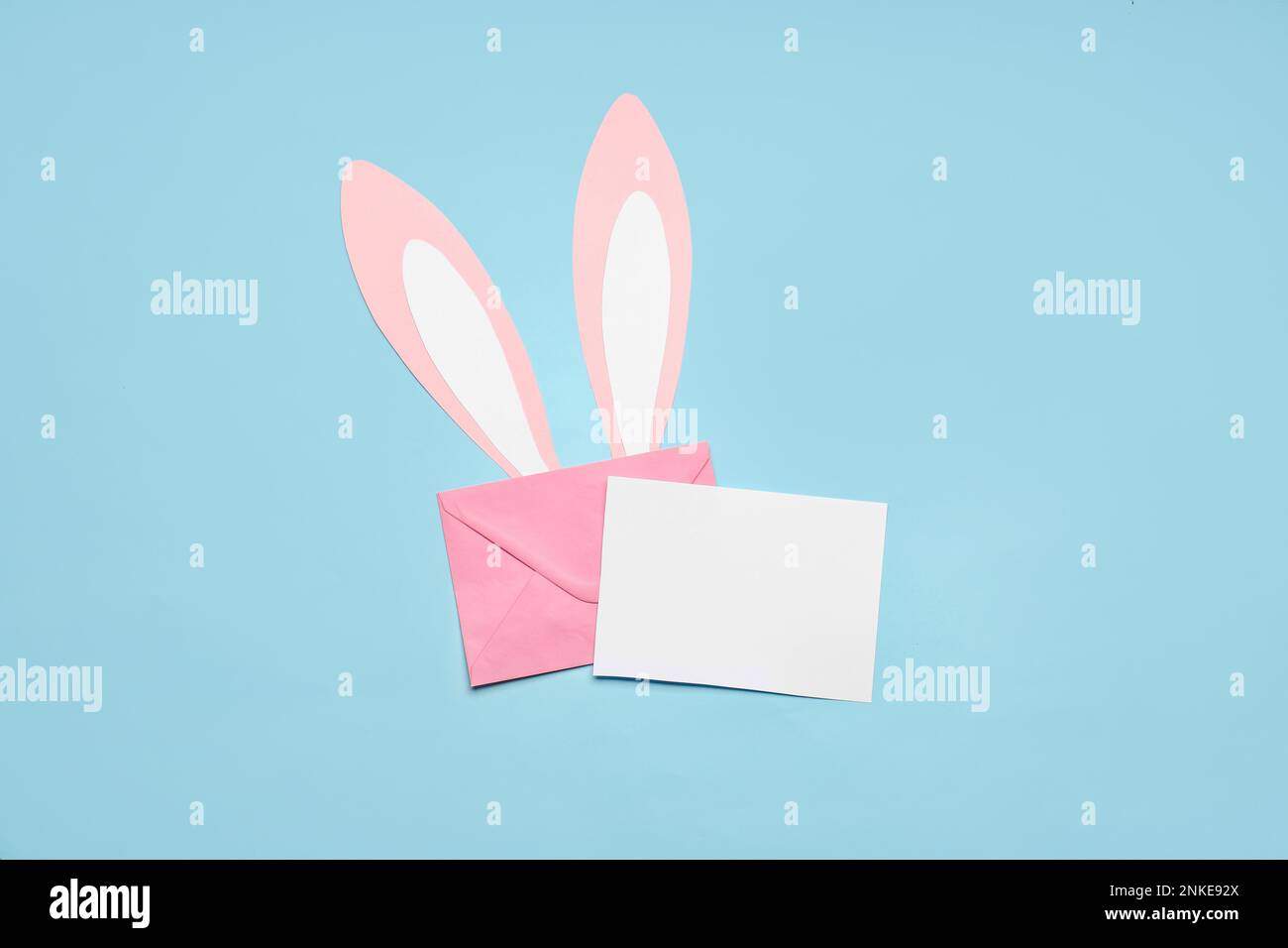 Composition with blank card, envelope and paper bunny ears on color ...