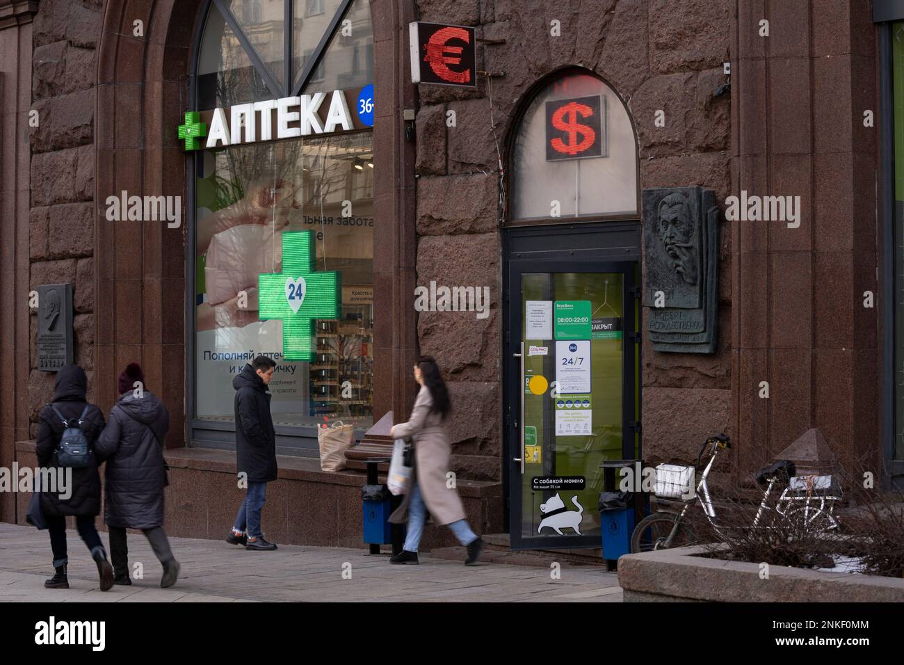 People walk past a pharmacy and a currency exchange on a main street in ...