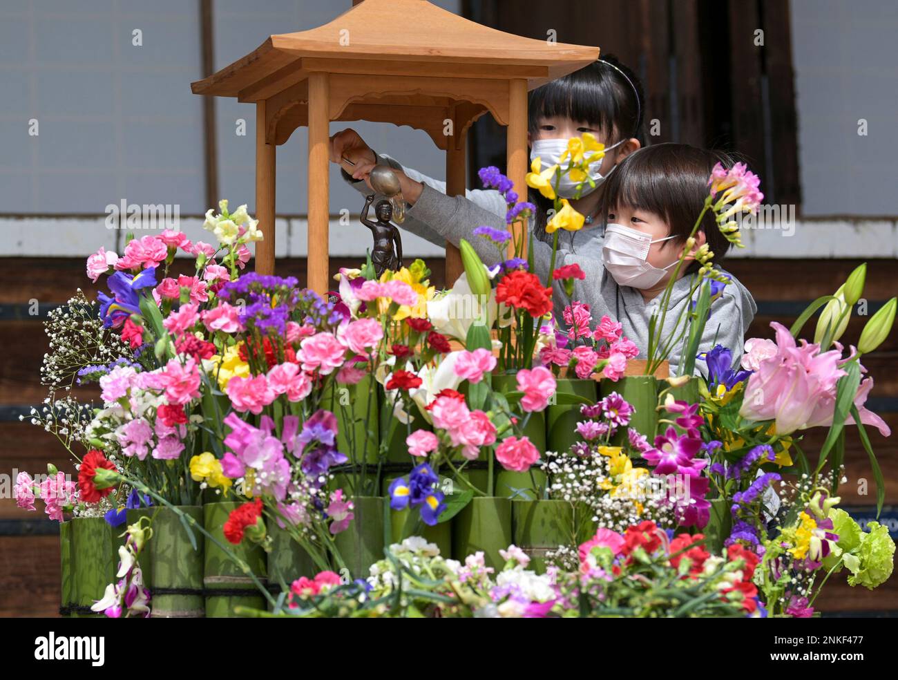 Worshippers spray a sweet tea on Hanamido, a small temple decorated ...