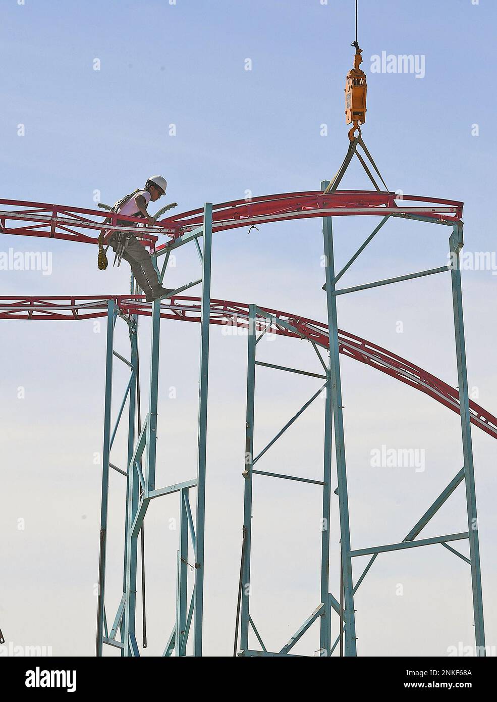 A Brown's Amusements worker, with the help of a crane, assembles a ...