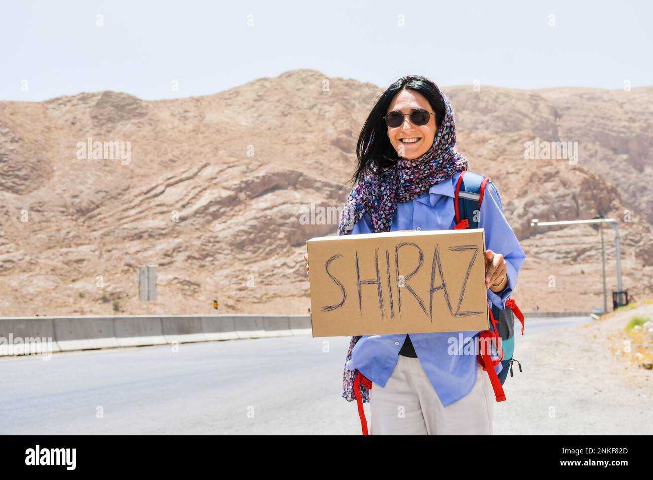 Young traveler woman stand on side of road hitchhike with sign to ...