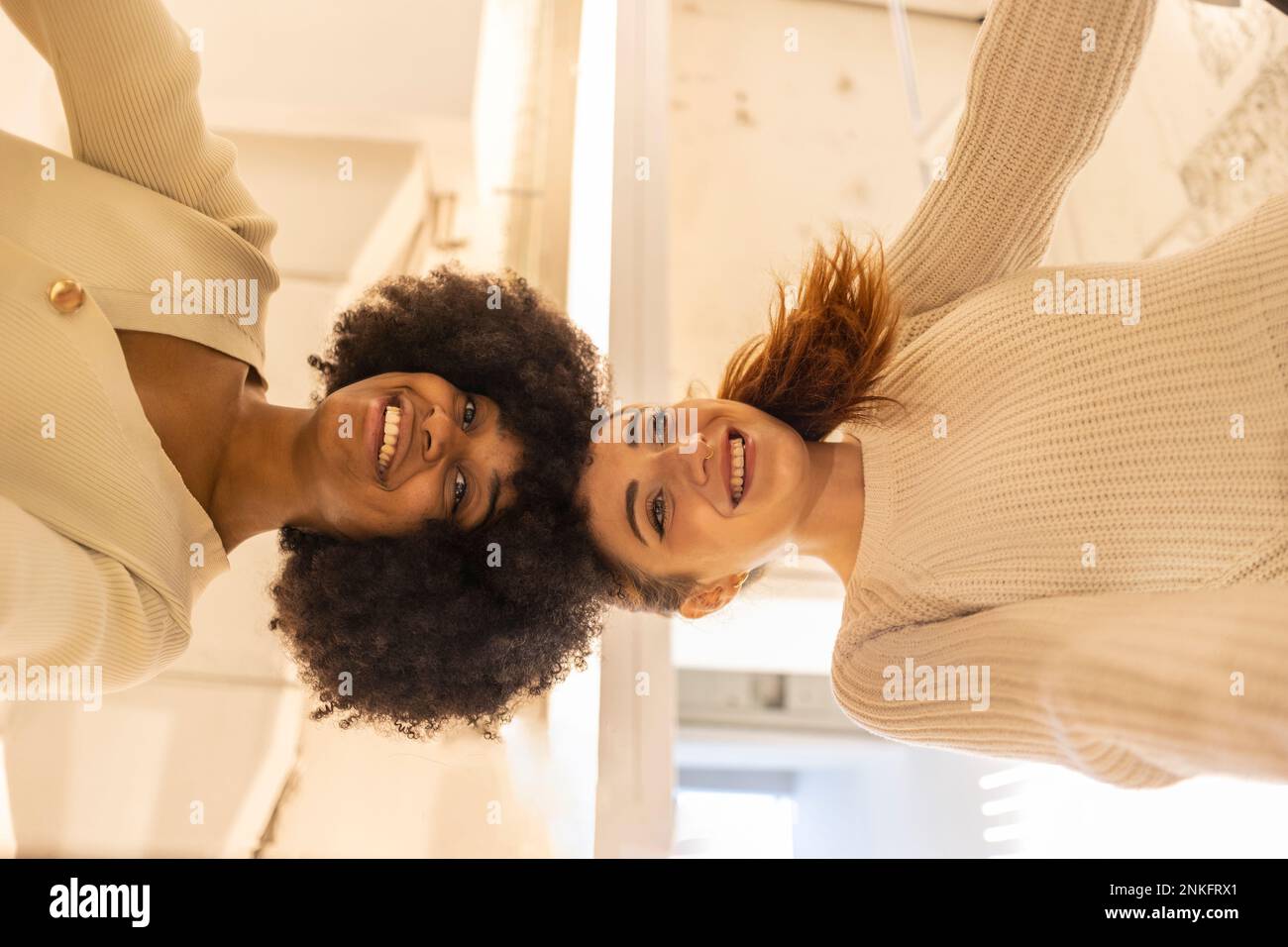 Cheerful young friends touching heads and standing together Stock Photo ...