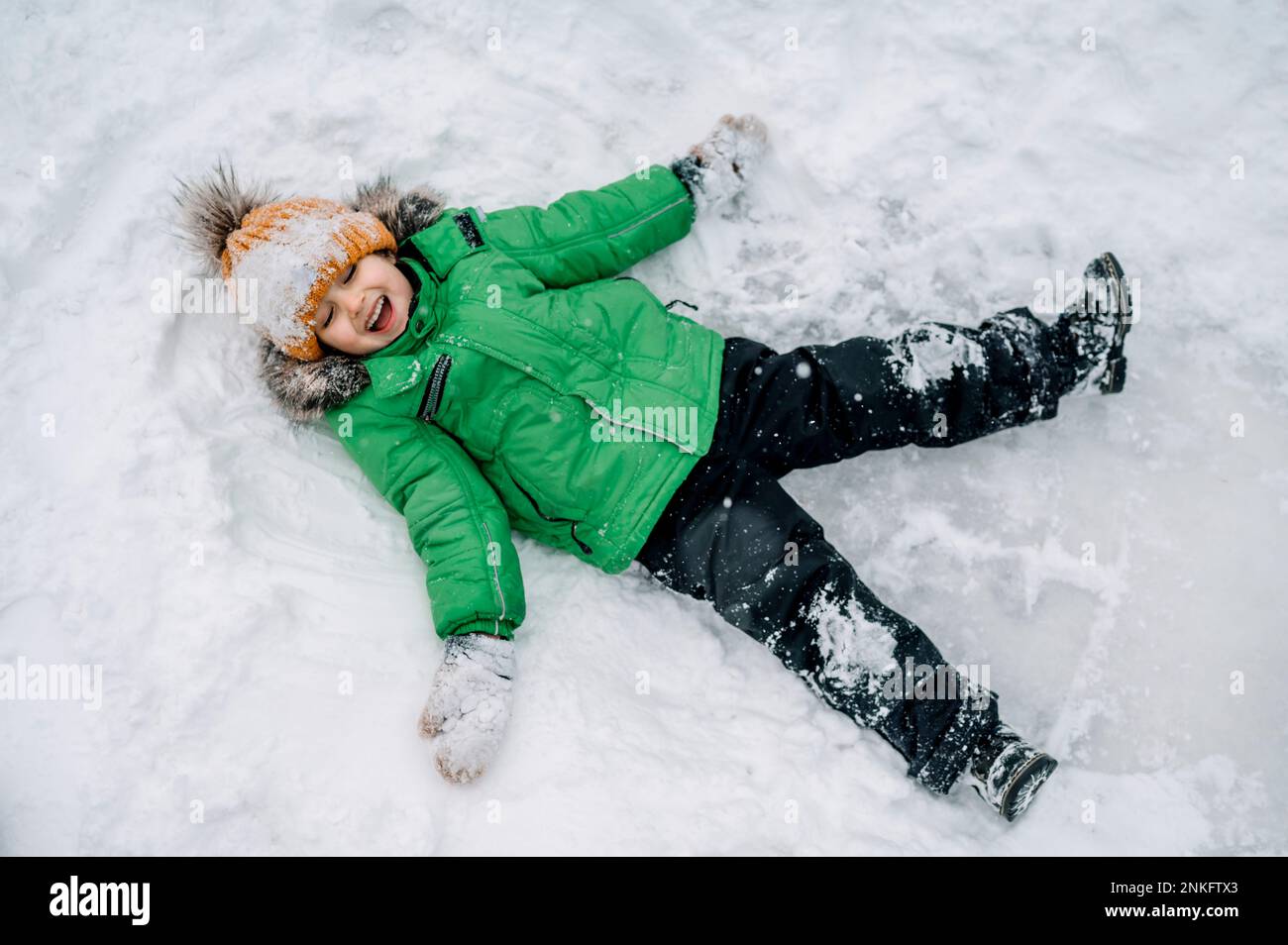 Cute boy making snow angel Stock Photo - Alamy