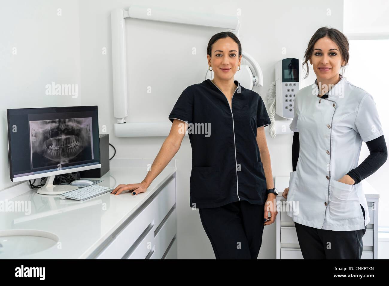 Female doctors standing together by desk at clinic Stock Photo - Alamy