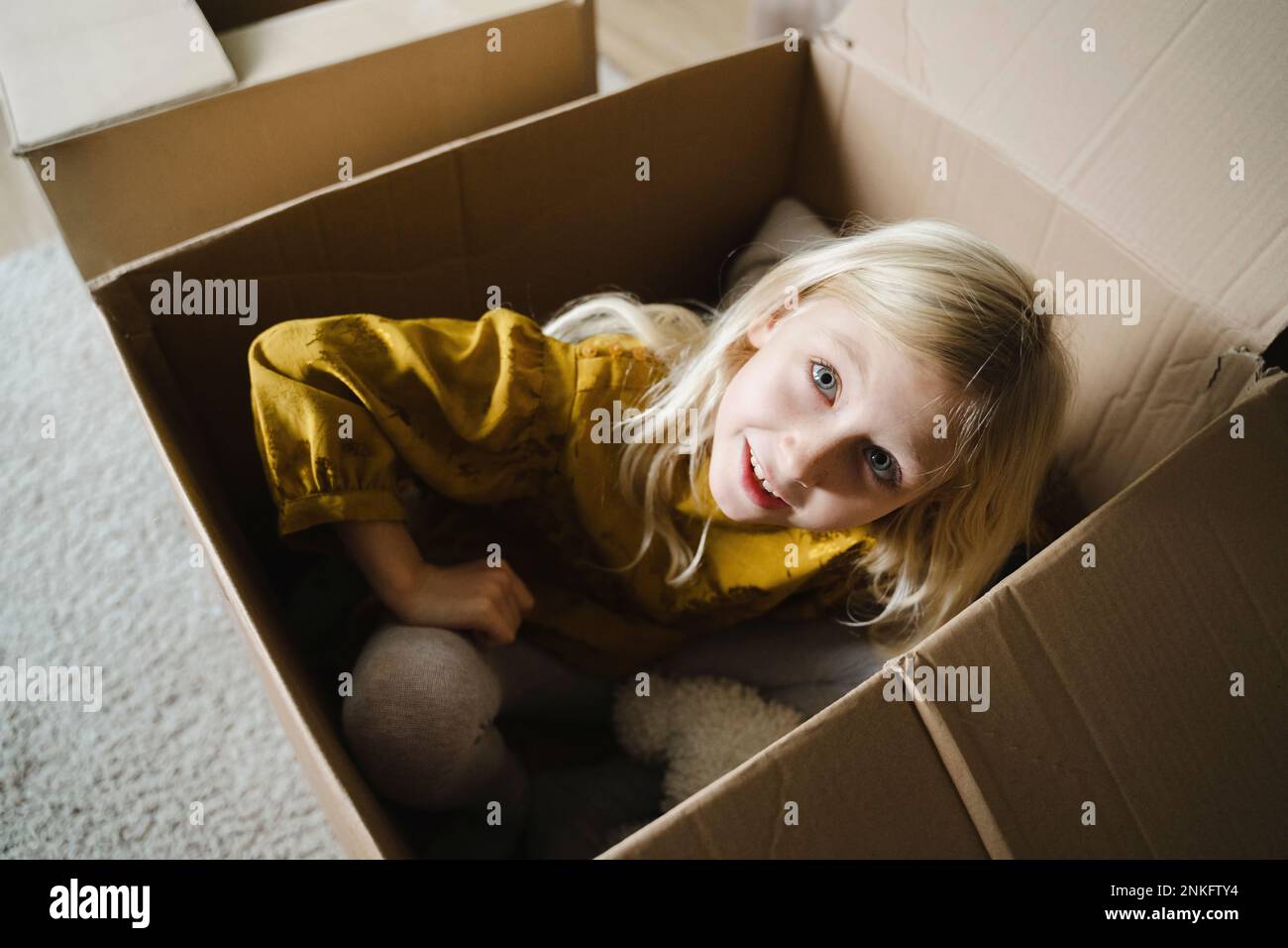 Girl sitting inside cardboard box at home Stock Photo - Alamy