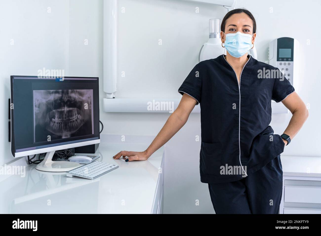 Doctor wearing surgical mask standing by desk at clinic Stock Photo - Alamy