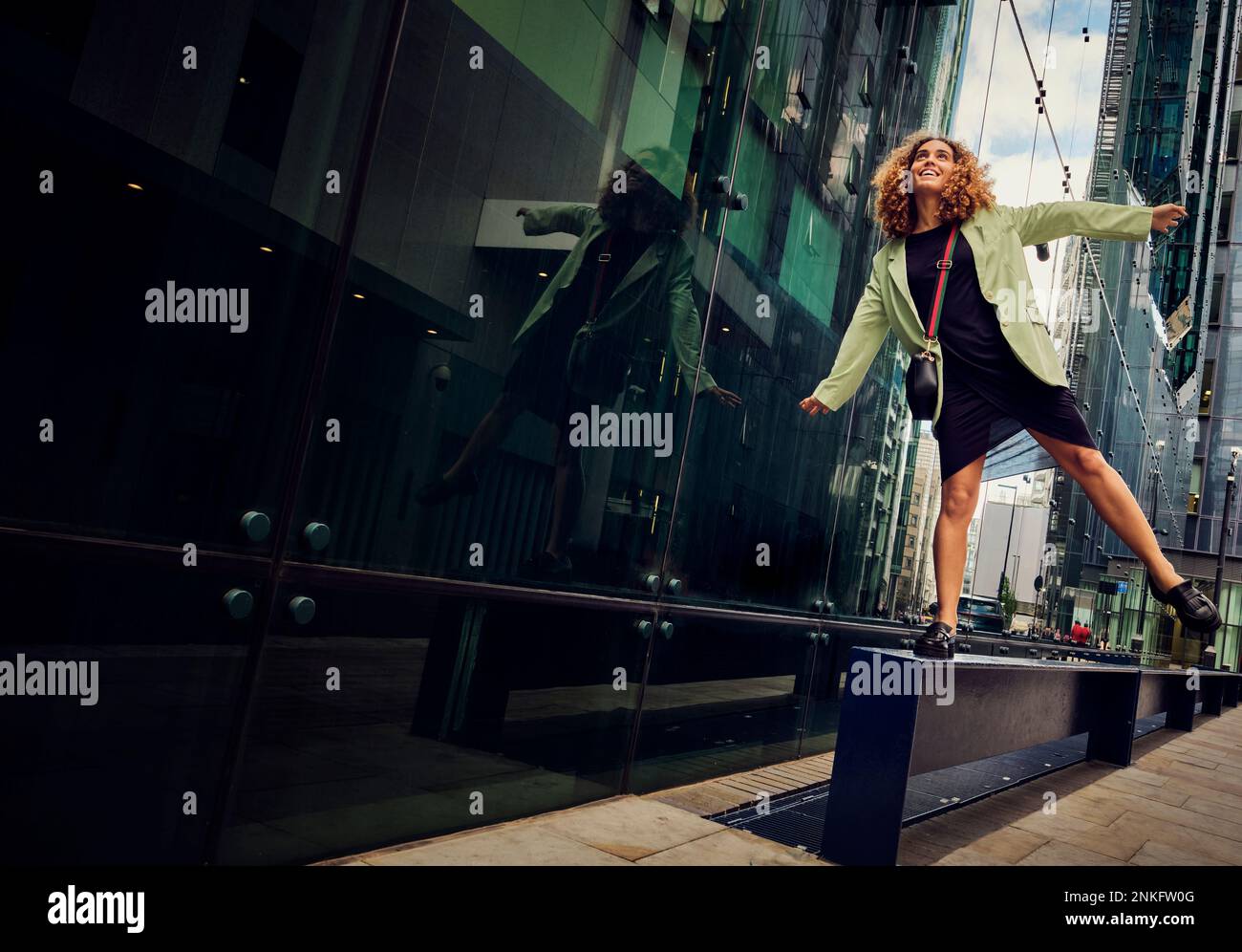 Playful businesswoman balancing on bench near office building Stock ...