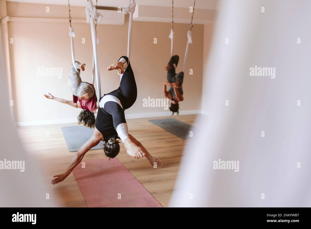 Women doing stretching exercise in aerial yoga class Stock Photo - Alamy