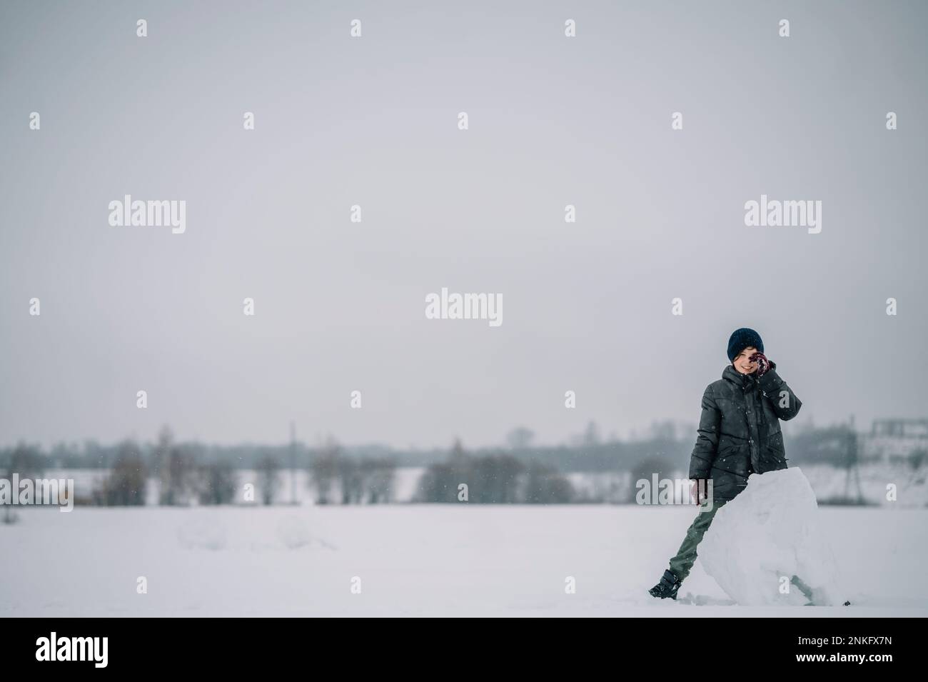 Boy standing by big lump of snow Stock Photo - Alamy