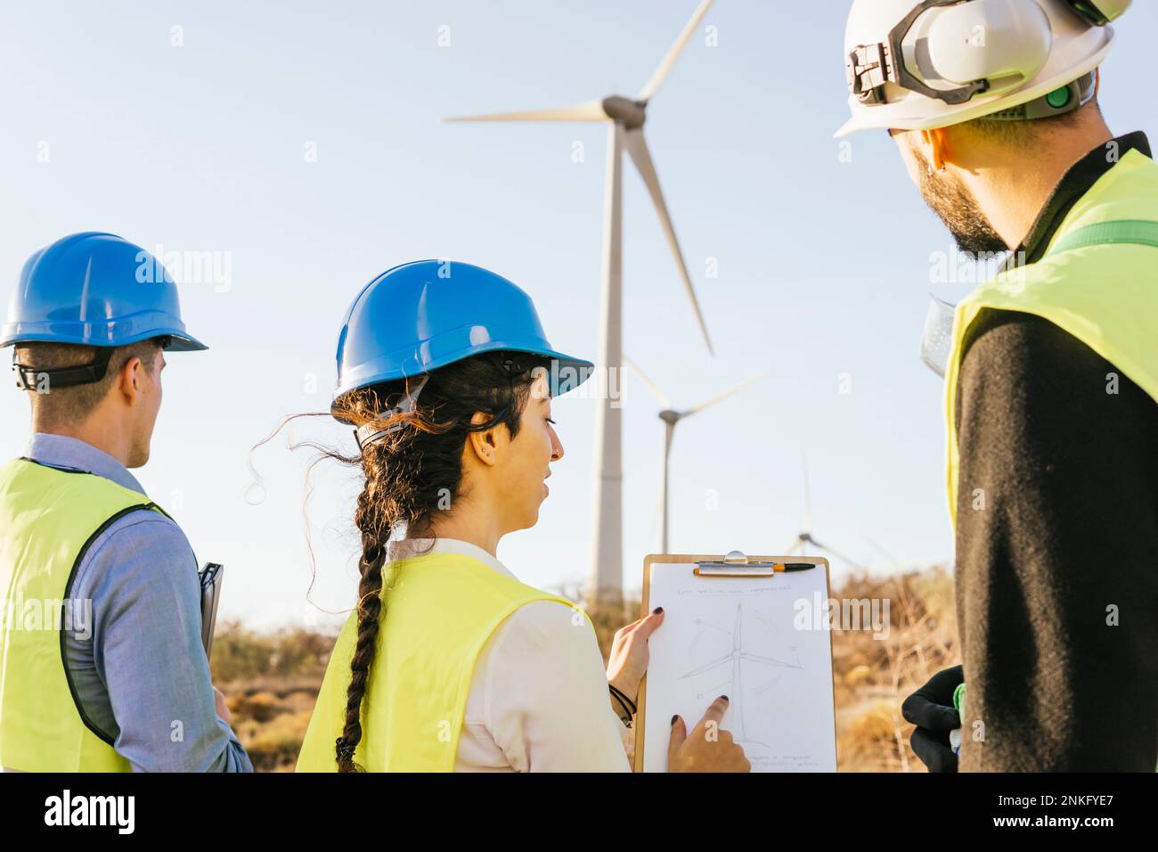 Engineers discussing with technician over wind turbine diagram Stock Photo - Alamy