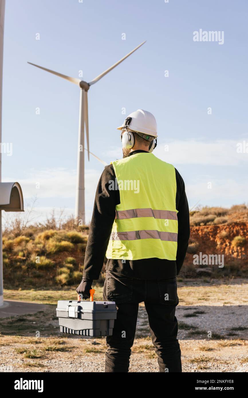 Technician with toolbox standing in front of wind turbine Stock Photo ...