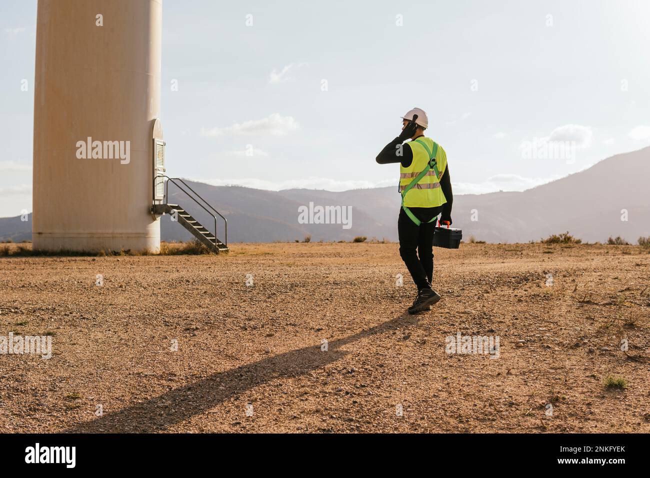 Technician with toolbox walking towards wind turbine Stock Photo - Alamy