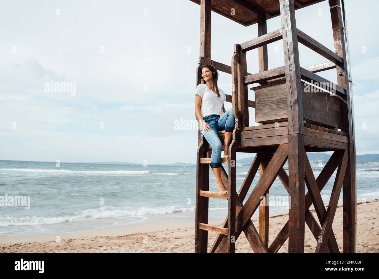 Woman sitting on lifeguard hut at beach Stock Photo - Alamy