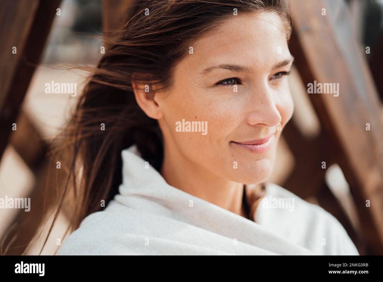 Contemplative woman smiling at beach Stock Photo - Alamy